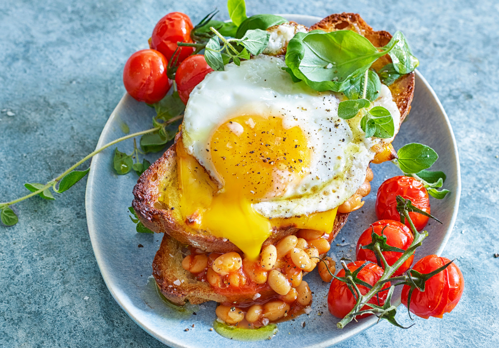 Toast med bønner i tomatsaus, gruyère og stekt egg servert med bakte ...